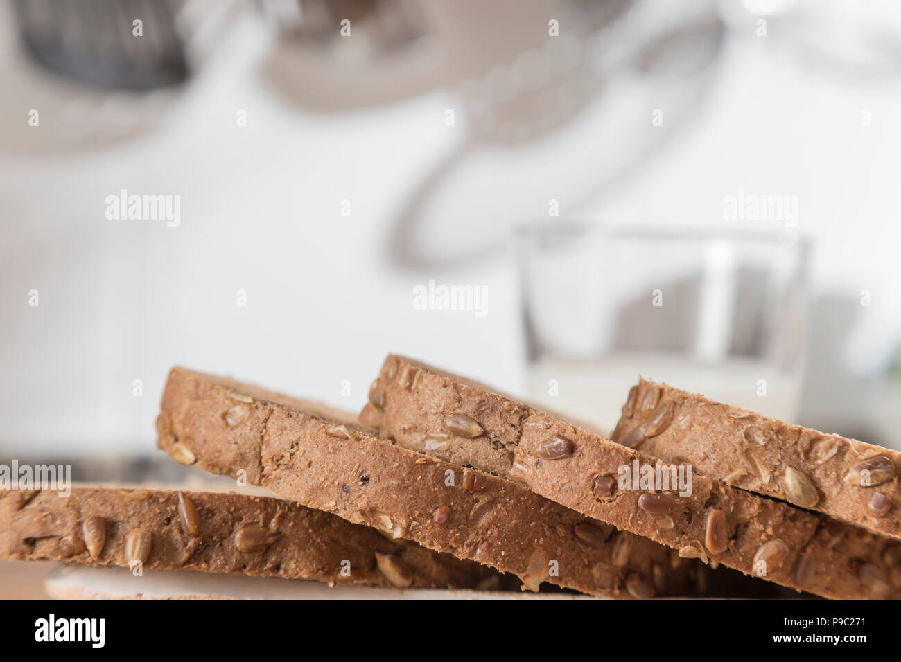 glass of milk and tray with several slices of wholemeal rye bread with ...