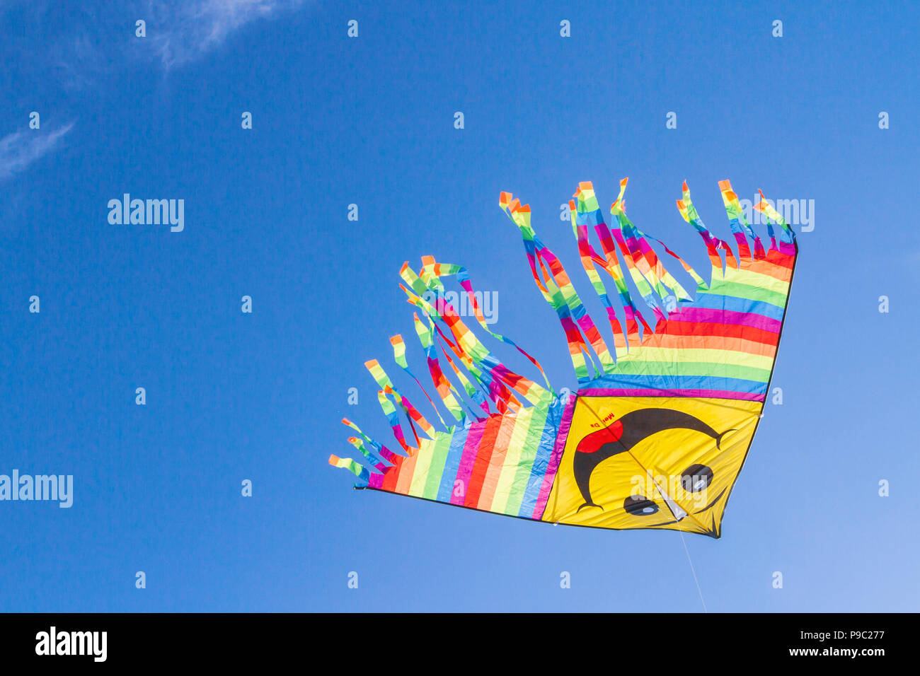 A fun and bright flying kite in the blue sky Stock Photo - Alamy