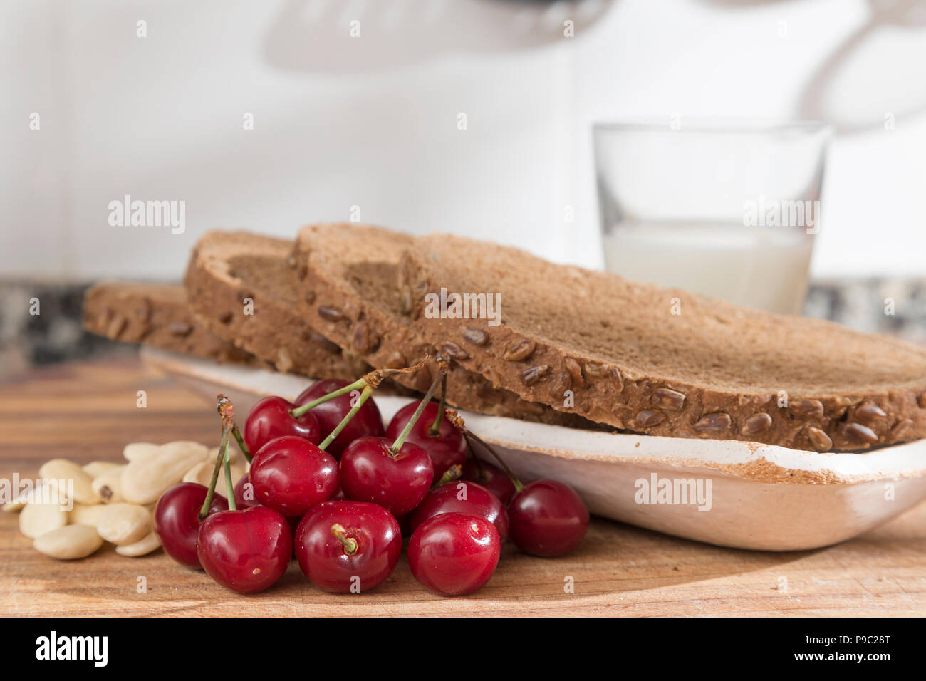 slices of wholemeal bread with pips, cherries, almonds and a glass of ...