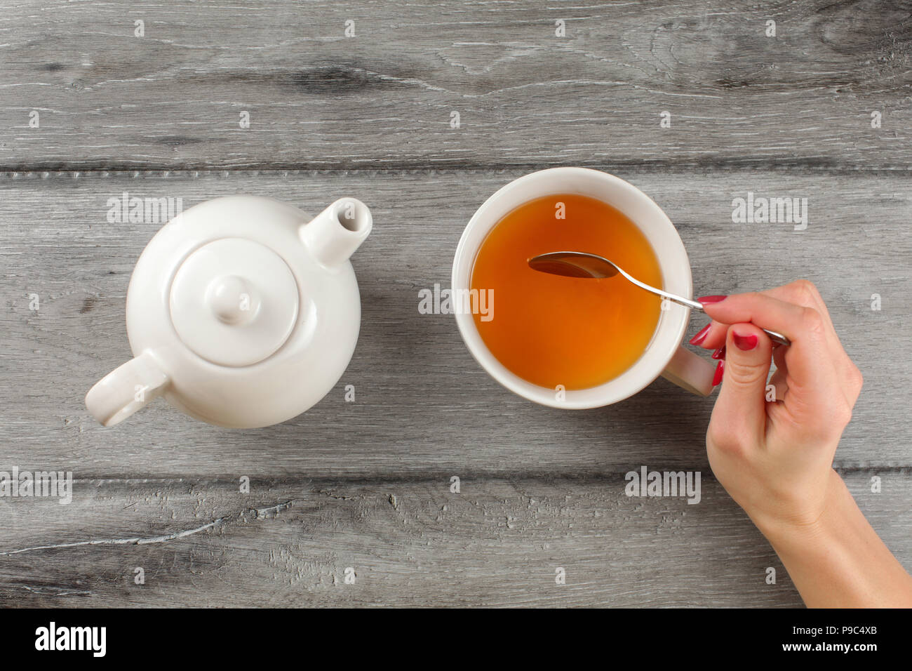 Table top view - woman hand holding spoon, stirring tea in white ...