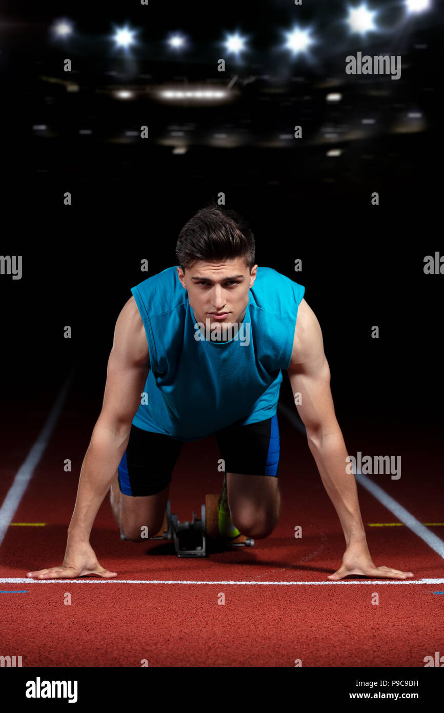 Sprinter leaving starting blocks on the running track in front of big ...