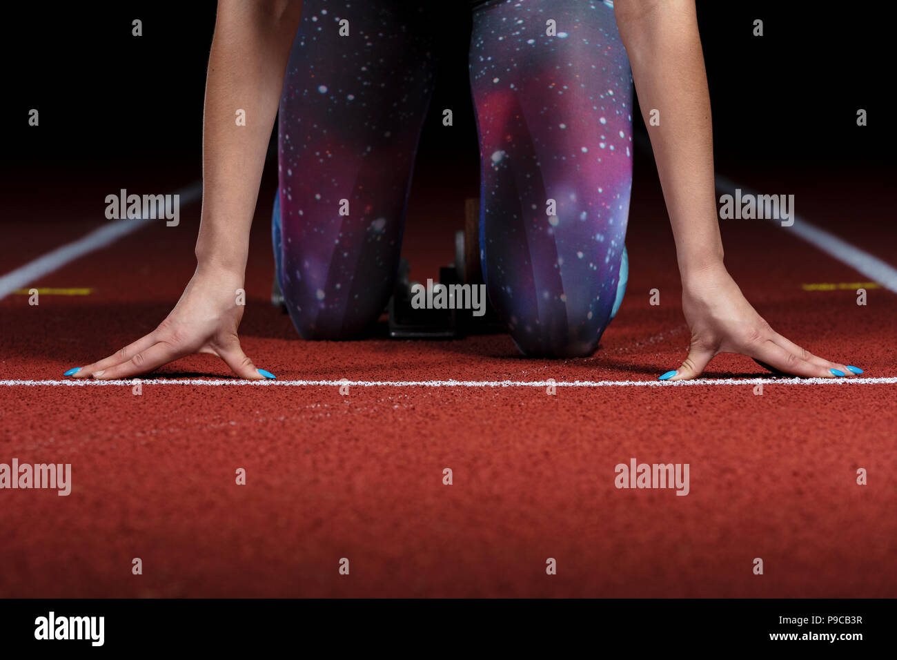 woman sprinter leaving starting blocks on the athletic track. exploding ...