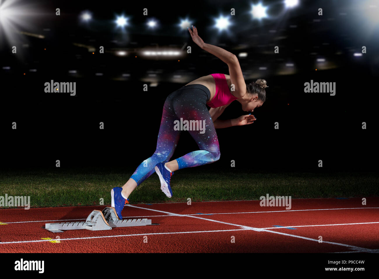 woman sprinter leaving starting blocks on the athletic track. exploding ...