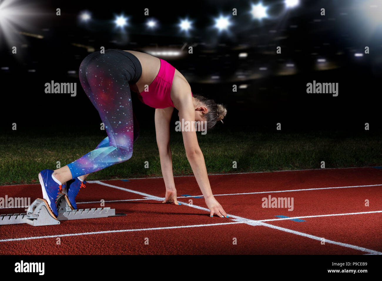 woman sprinter leaving starting blocks on the athletic track. exploding ...