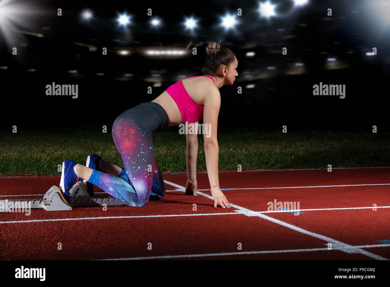 woman sprinter leaving starting blocks on the athletic track. exploding ...