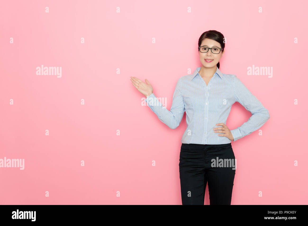 businesswoman showing the presentation gesture isolated on pink ...