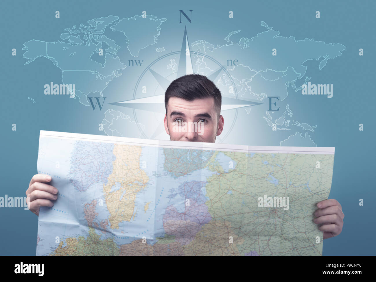 Handsome young man holding a map with a world map and a compass behind ...