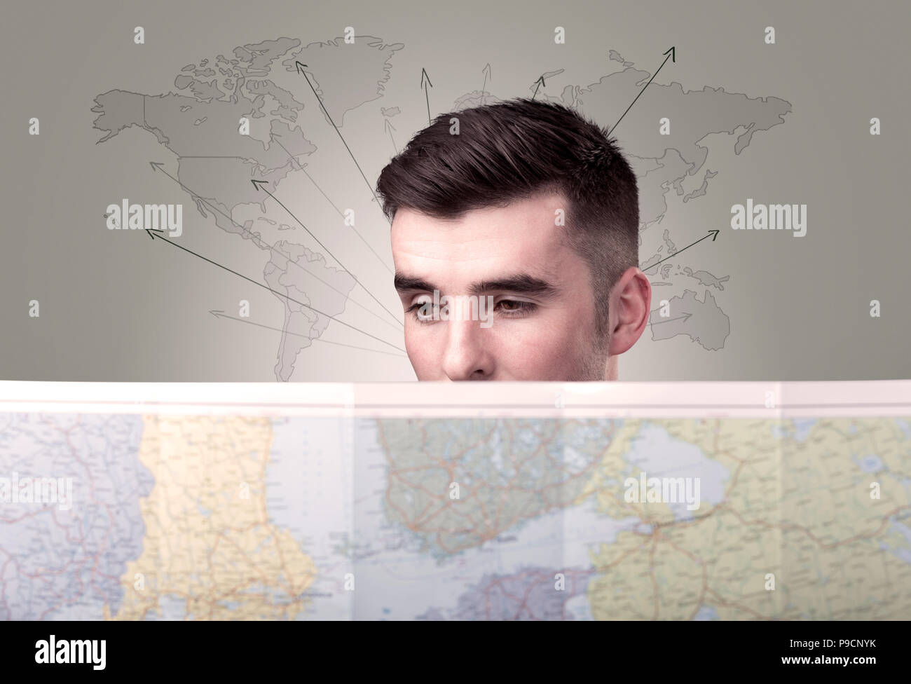 Handsome young man holding a map with world map and arrows behind him ...