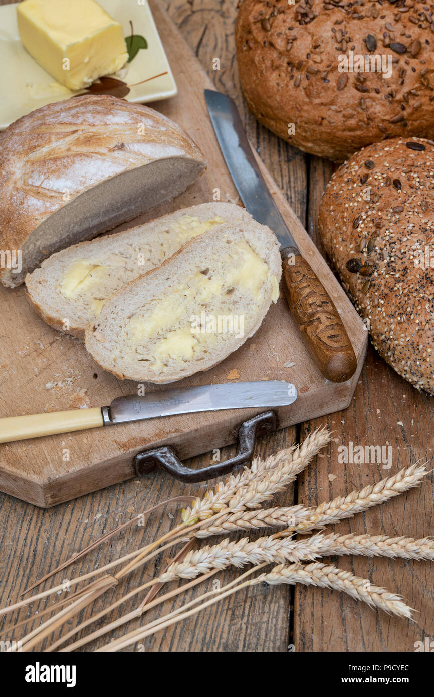 Sliced White bread with seeded loaves on a bread board with wheat and a ...