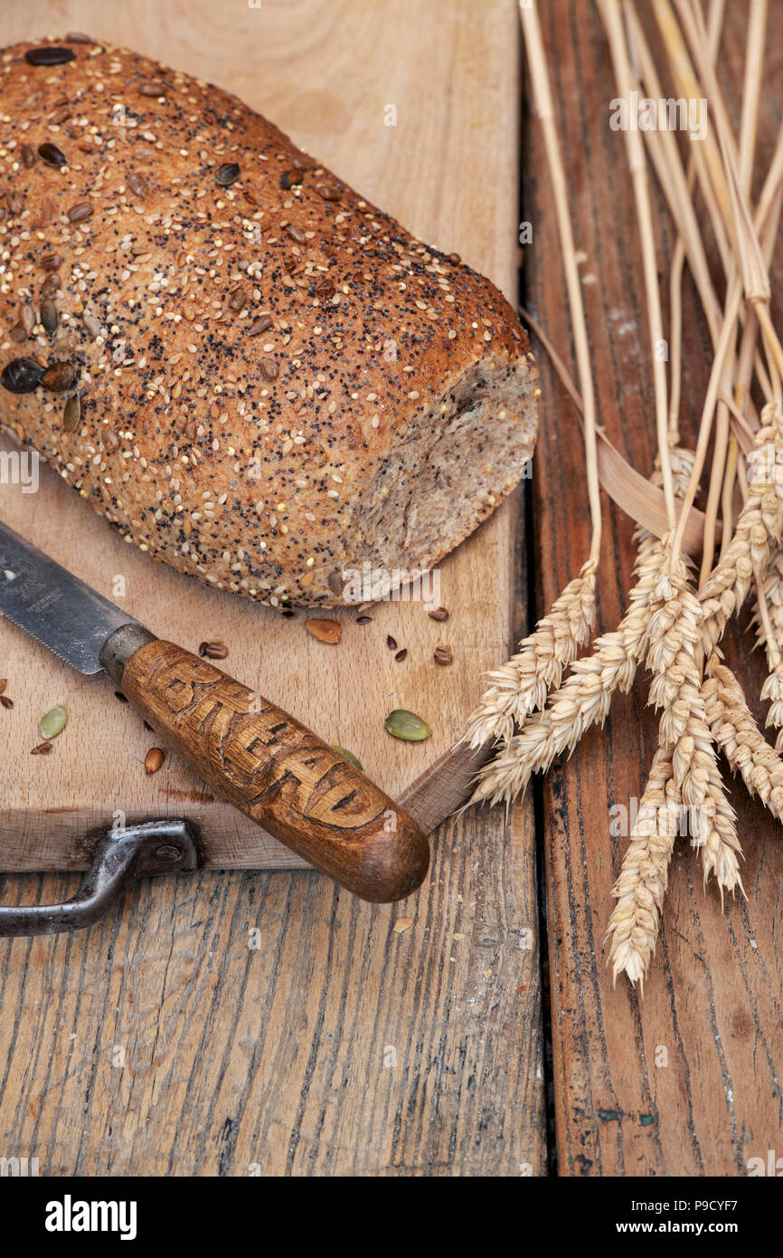 Seeded bread on a bread board with wheat and a bread knife. UK Stock ...