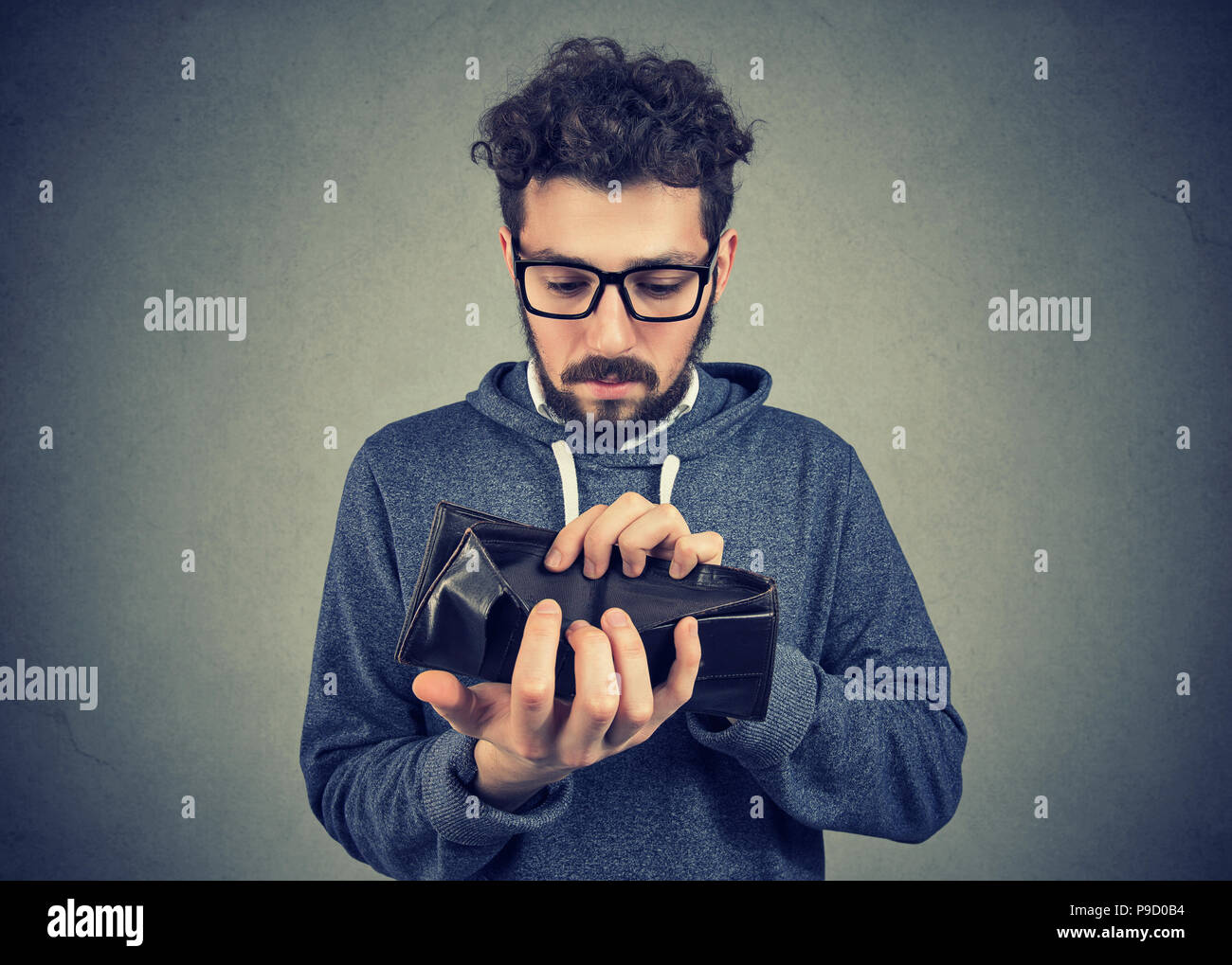 Sad man with no money holding an empty wallet Stock Photo - Alamy