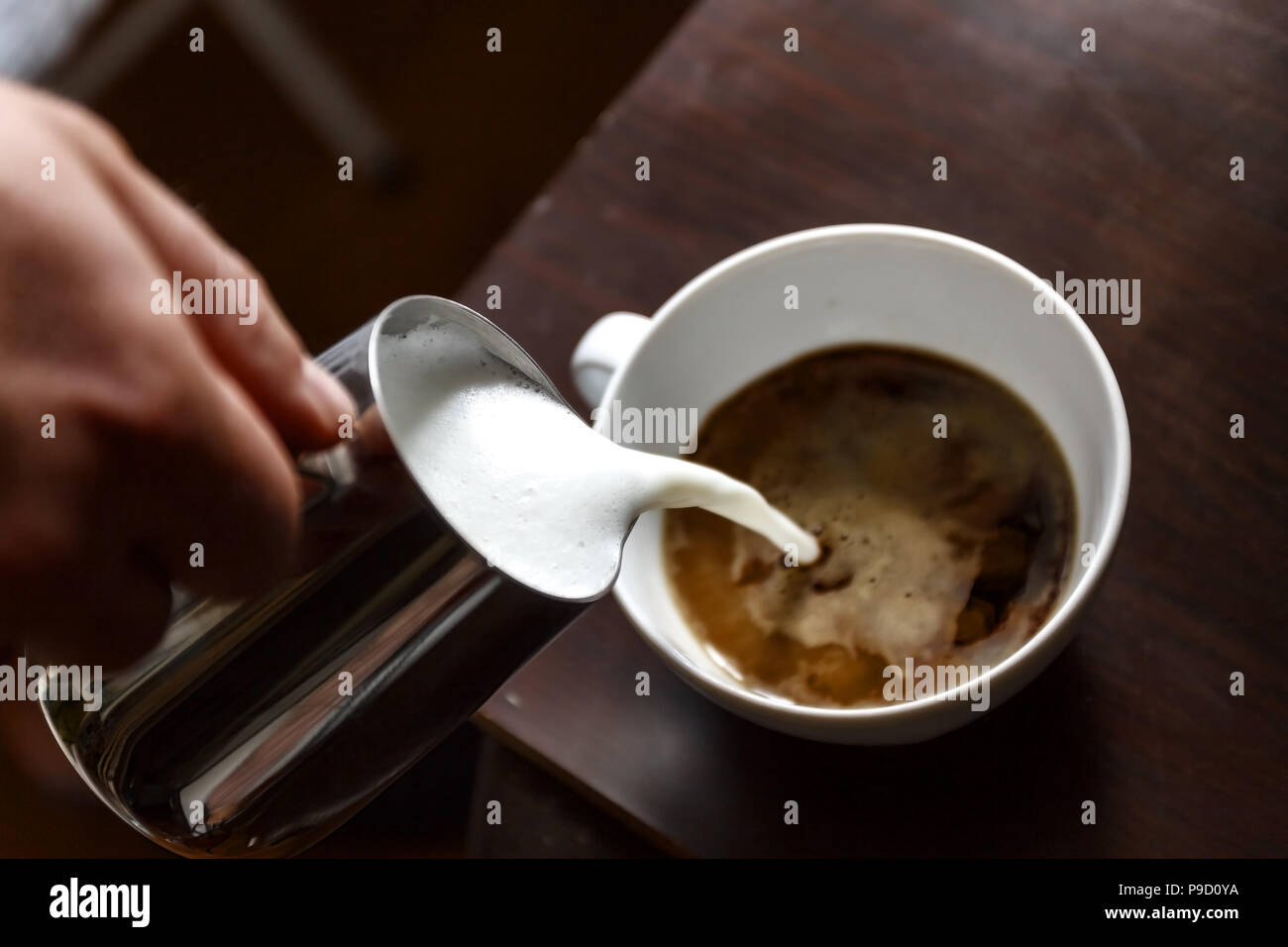 man pouring into a cup of coffee with milk Stock Photo - Alamy