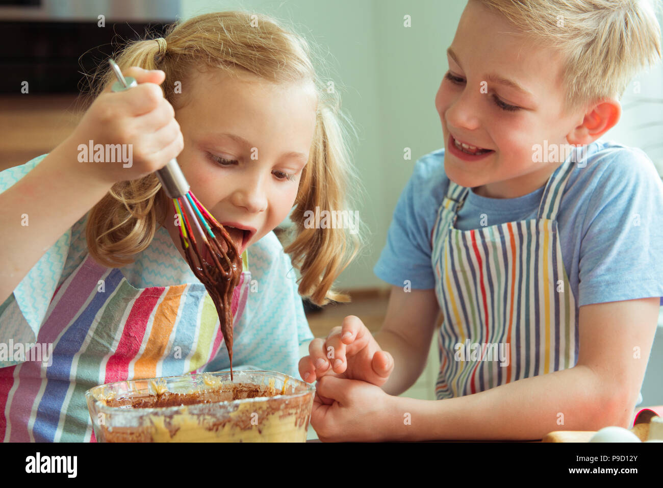 Two happy children having fun and taste chocolate dough in the modern ...