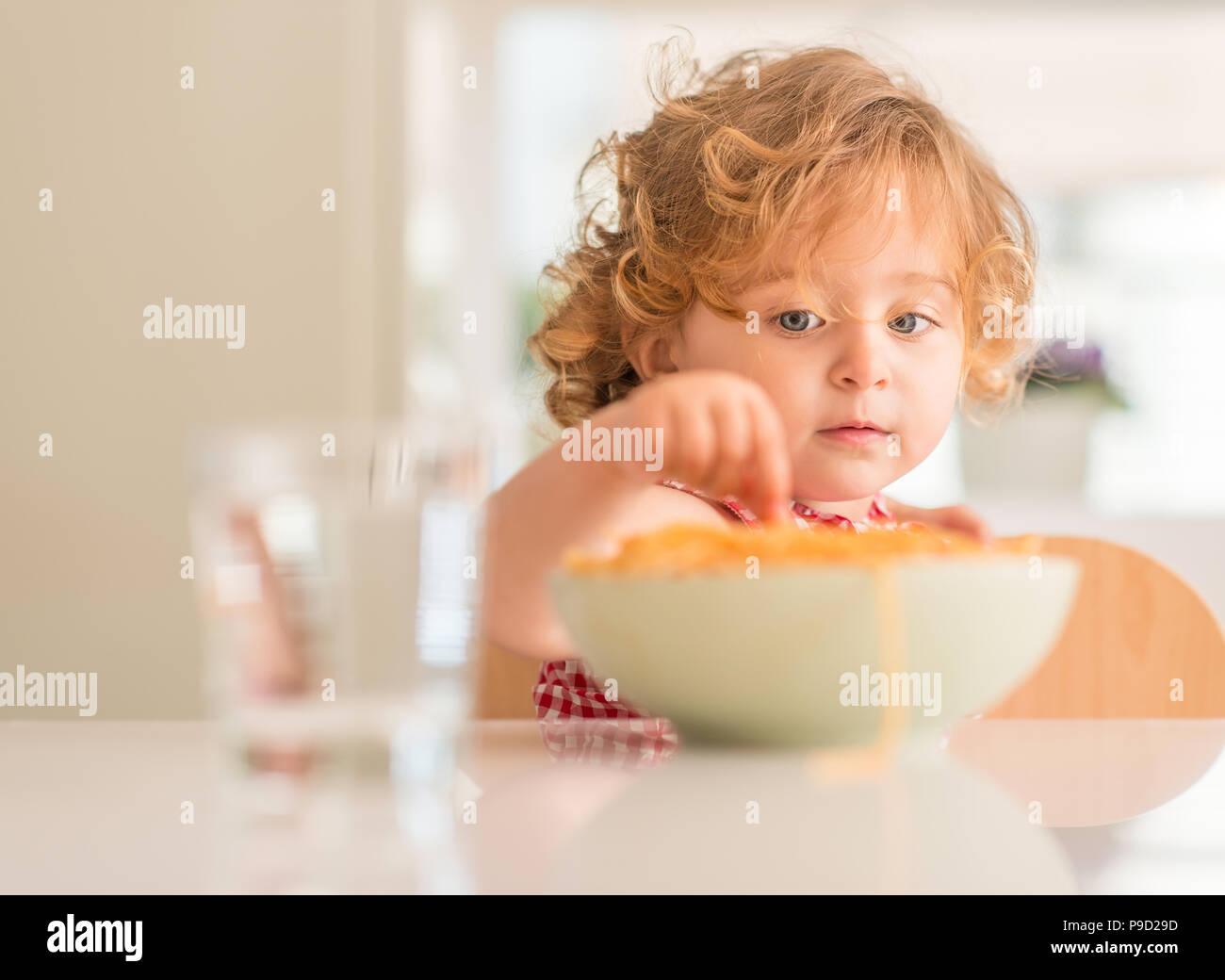 Beautiful child eating spaghetti with hands at home Stock Photo - Alamy