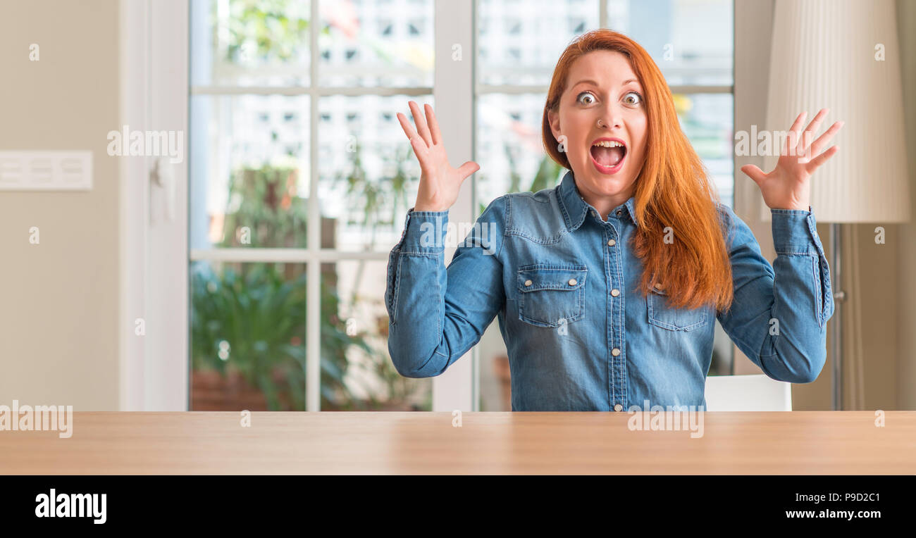 Redhead woman at home celebrating crazy and amazed for success with ...