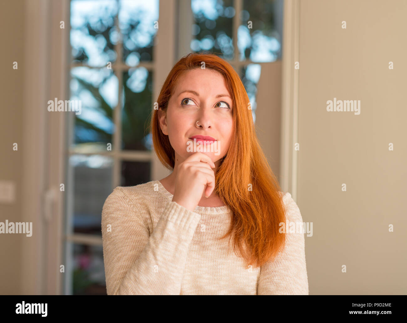 Redhead woman at home serious face thinking about question, very ...