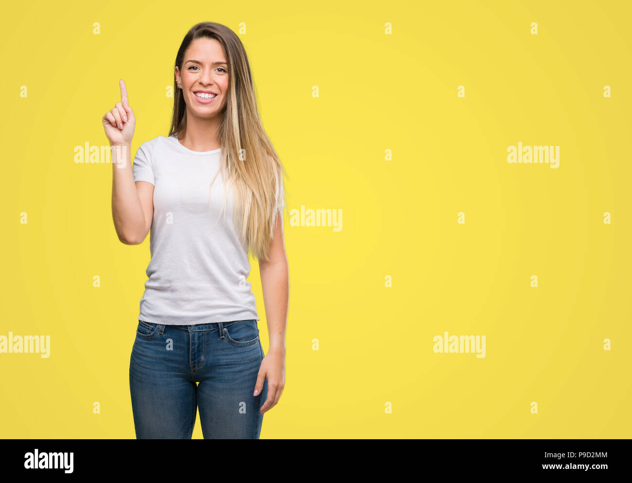 Beautiful young woman wearing t-shirt and jeans surprised with an idea ...