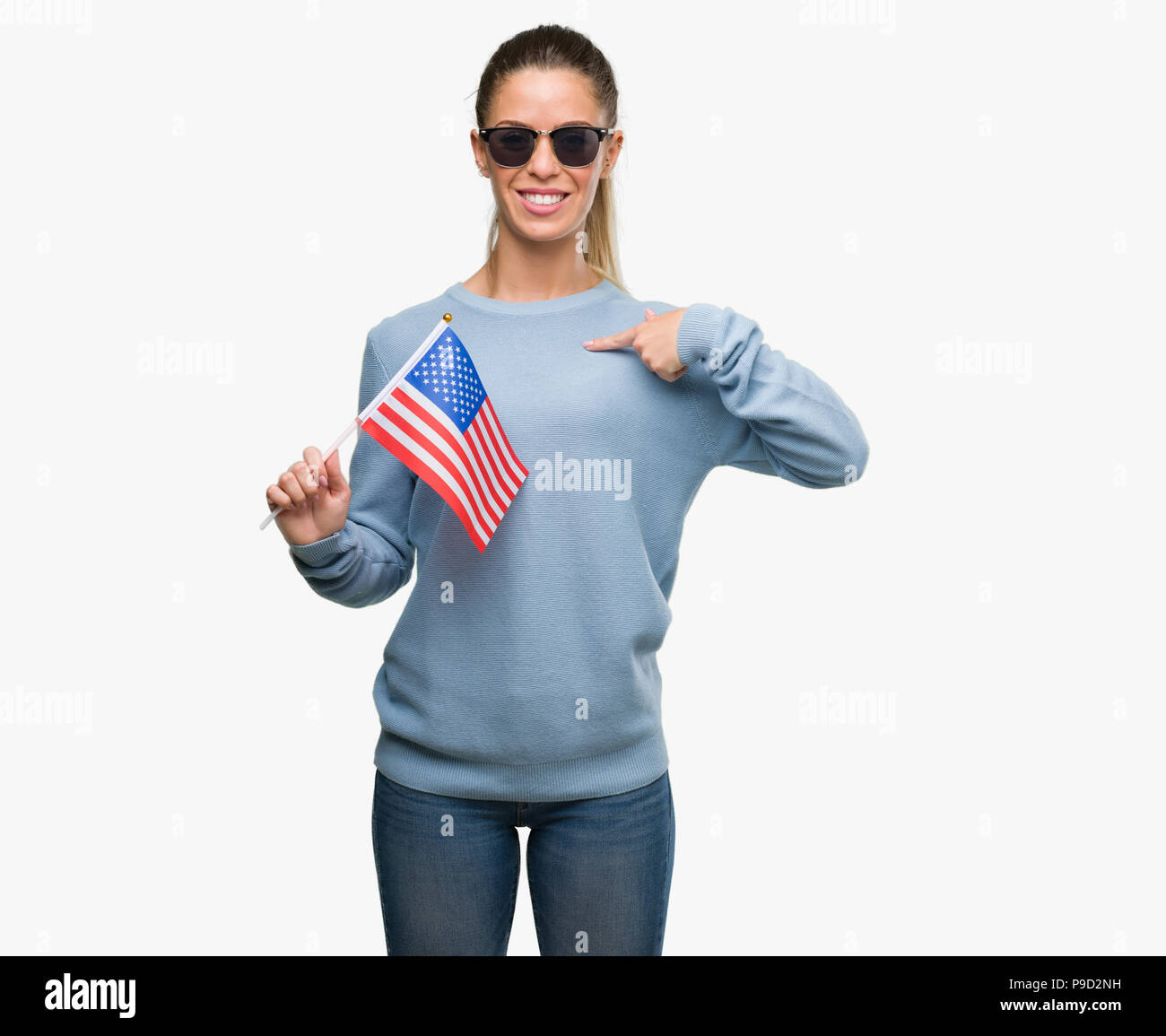 Beautiful young woman holding USA flag with surprise face pointing ...