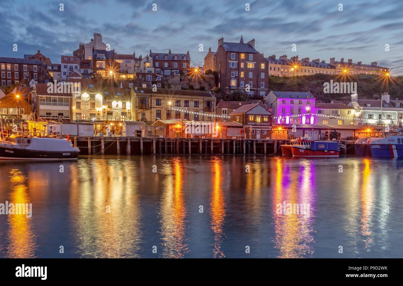 A scene of the town and harbour of Whitby lit up at nighttime. The ...