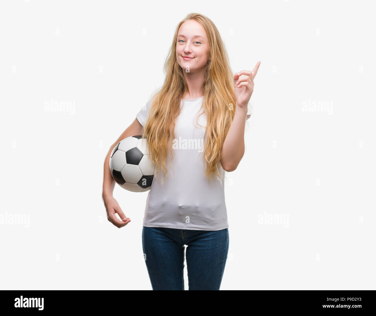 Blonde teenager woman holding soccer football ball surprised with an ...