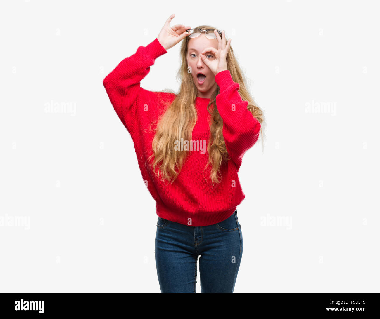 Blonde teenager woman wearing red sweater doing ok gesture shocked with ...