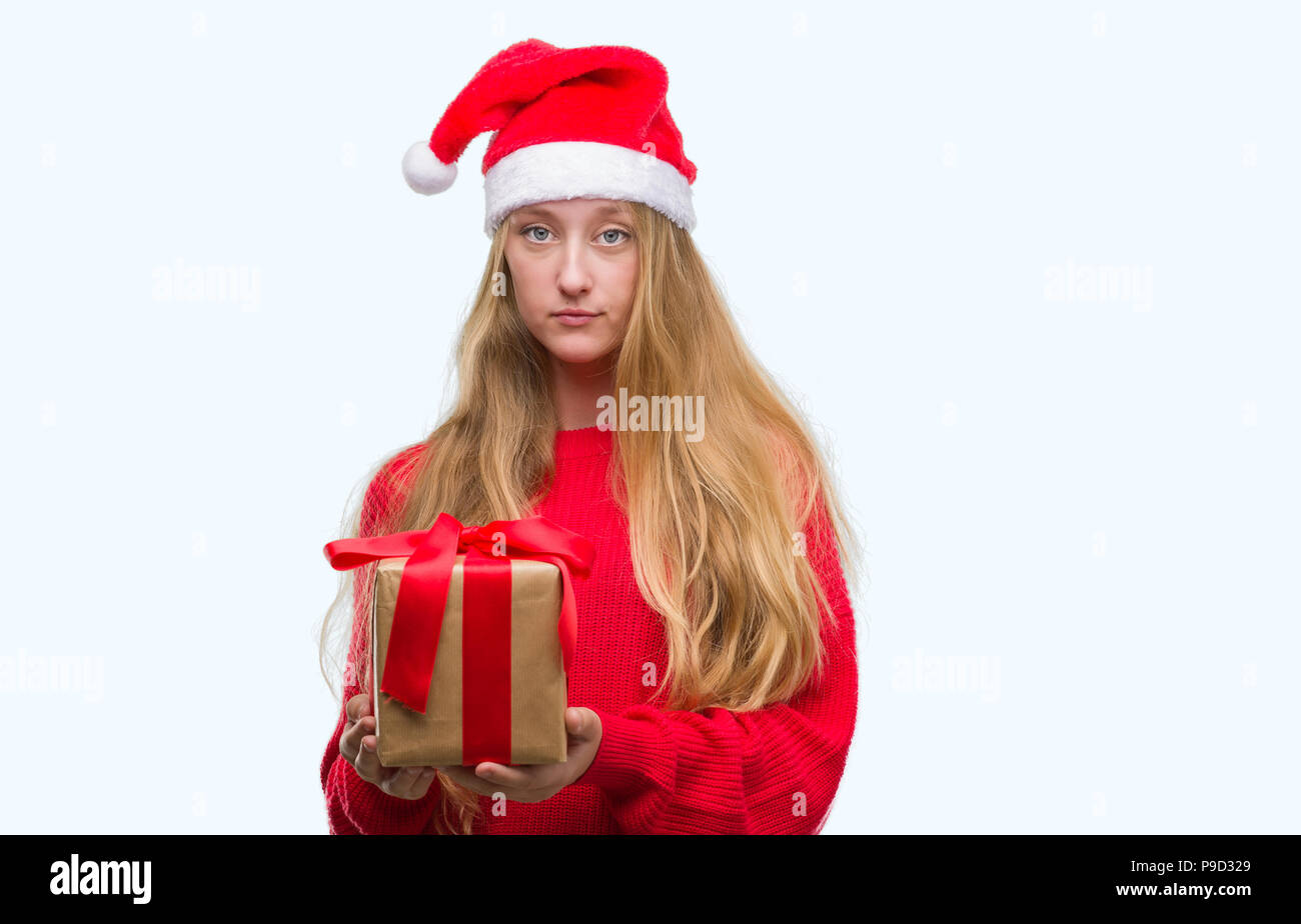 Blonde teenager woman wearing santa claus hat with a confident ...