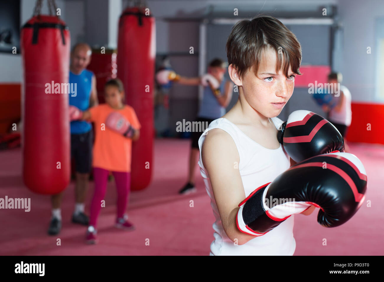 Teenage boxer in gloves posing during boxing training at gym Stock ...