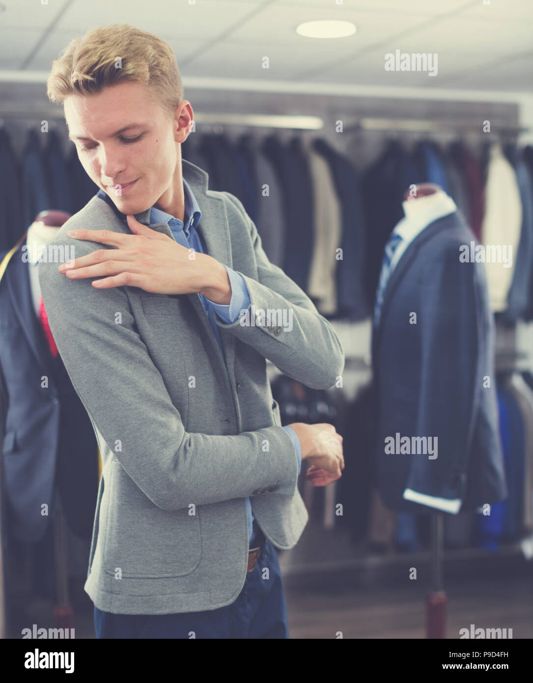 Male in suit trying business jacket in the clothes store looking mirror ...