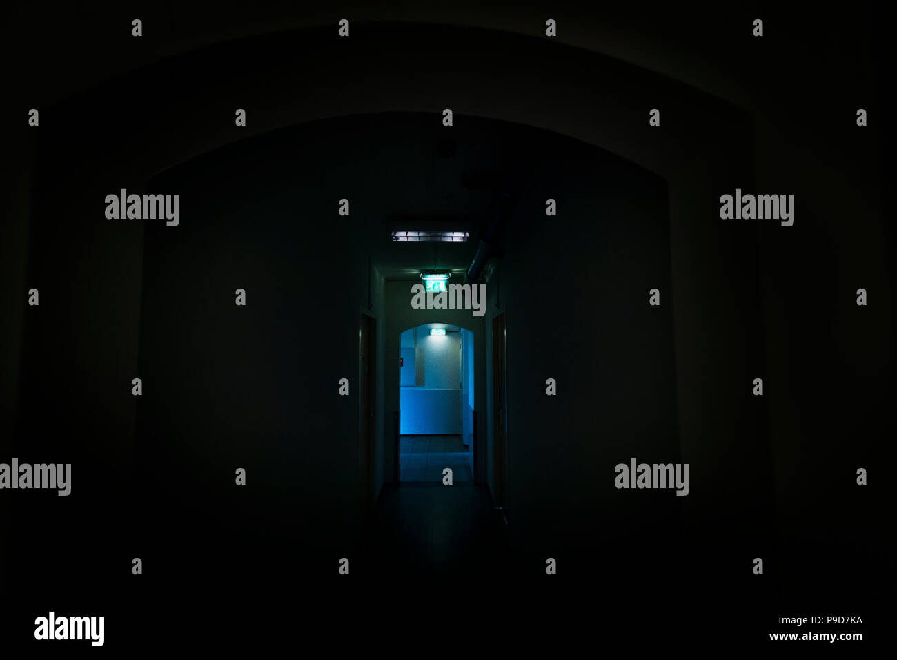 Narrow hallway with a sign showing emergency exit Stock Photo - Alamy