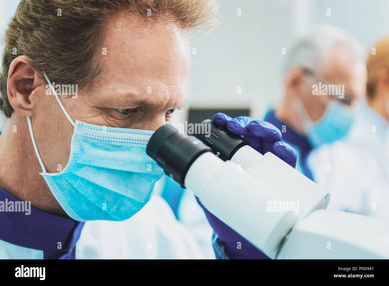 Close up of serious scientist that looking into microscope Stock Photo ...
