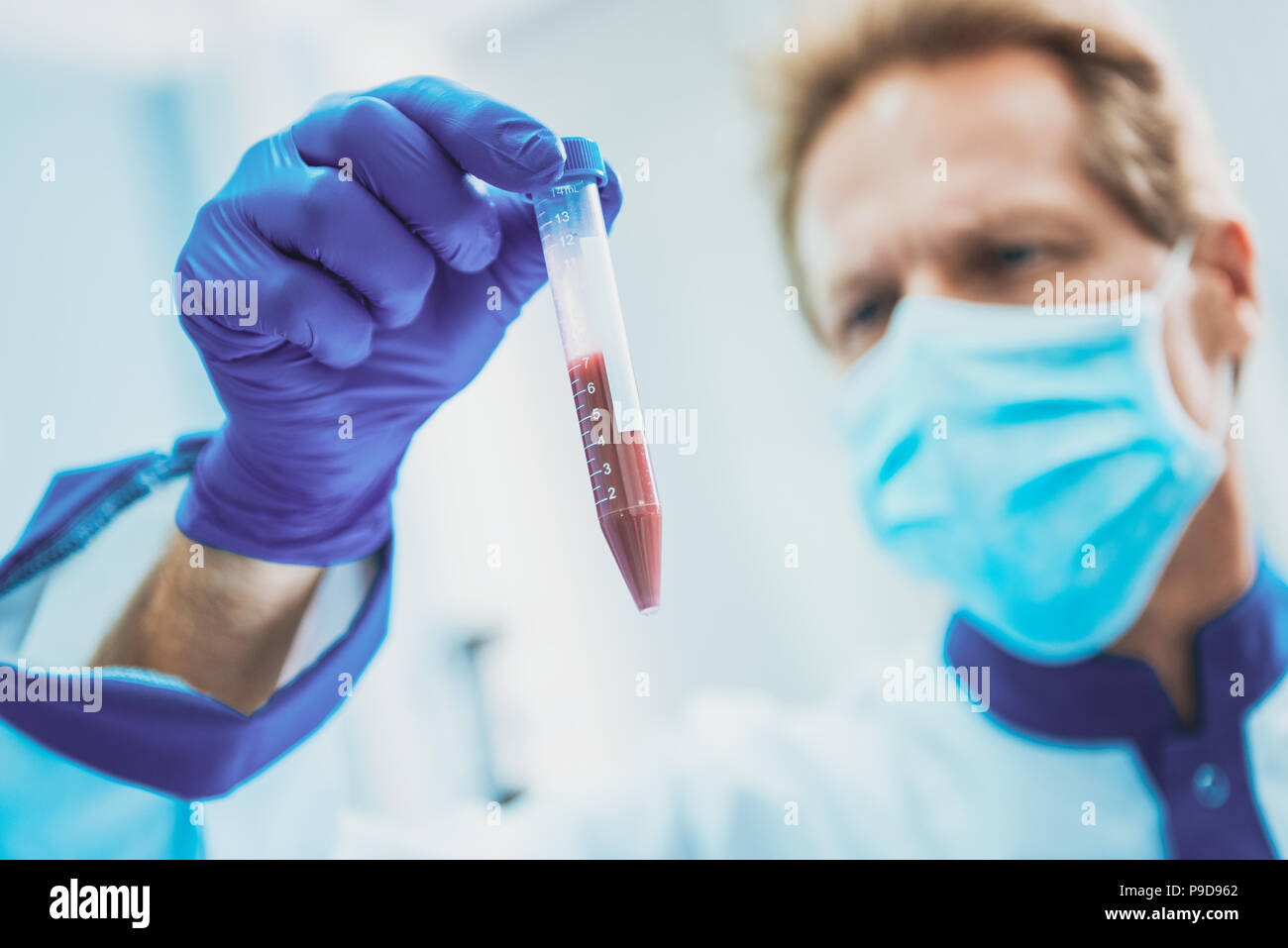 Serious scientist looking at test tube Stock Photo - Alamy