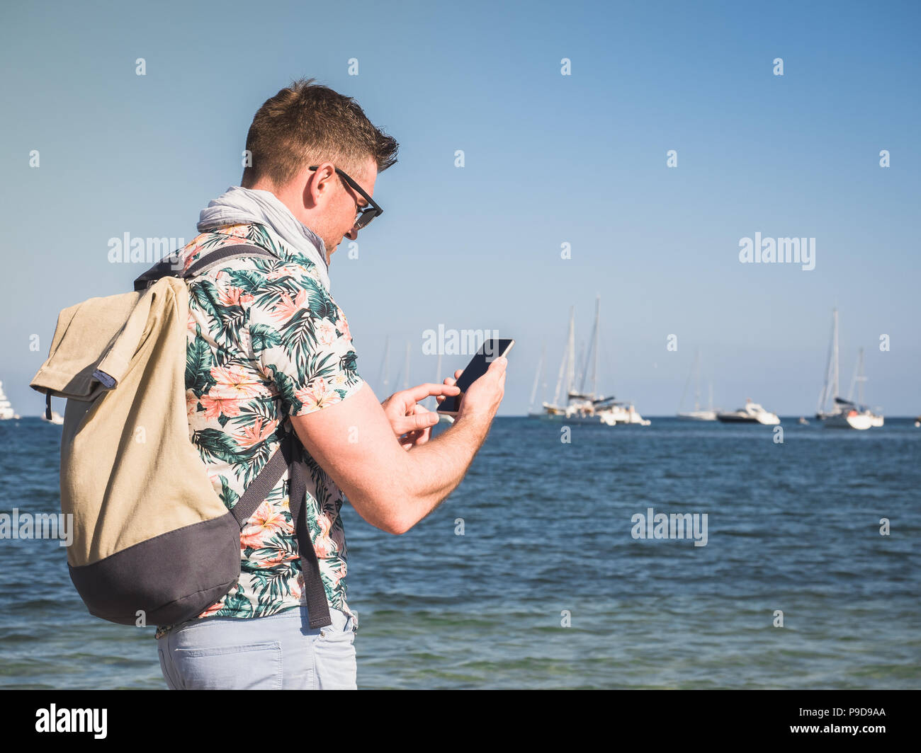 Happy, smiling man with a backpack and smartphone on the background of ...