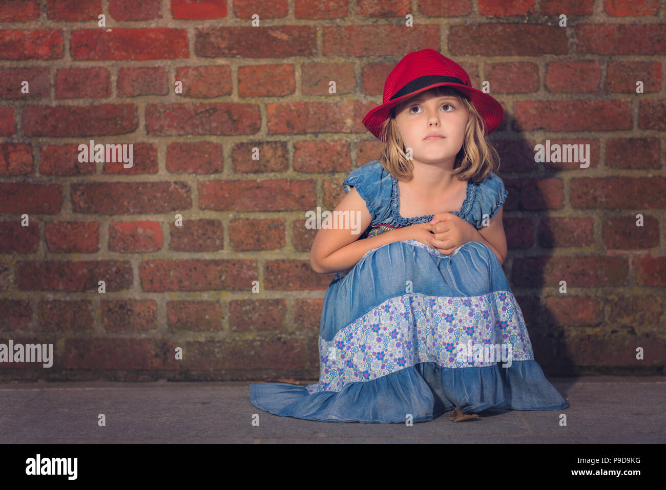 Cute little Caucasian girl looking sad resting by a brick wall Stock ...