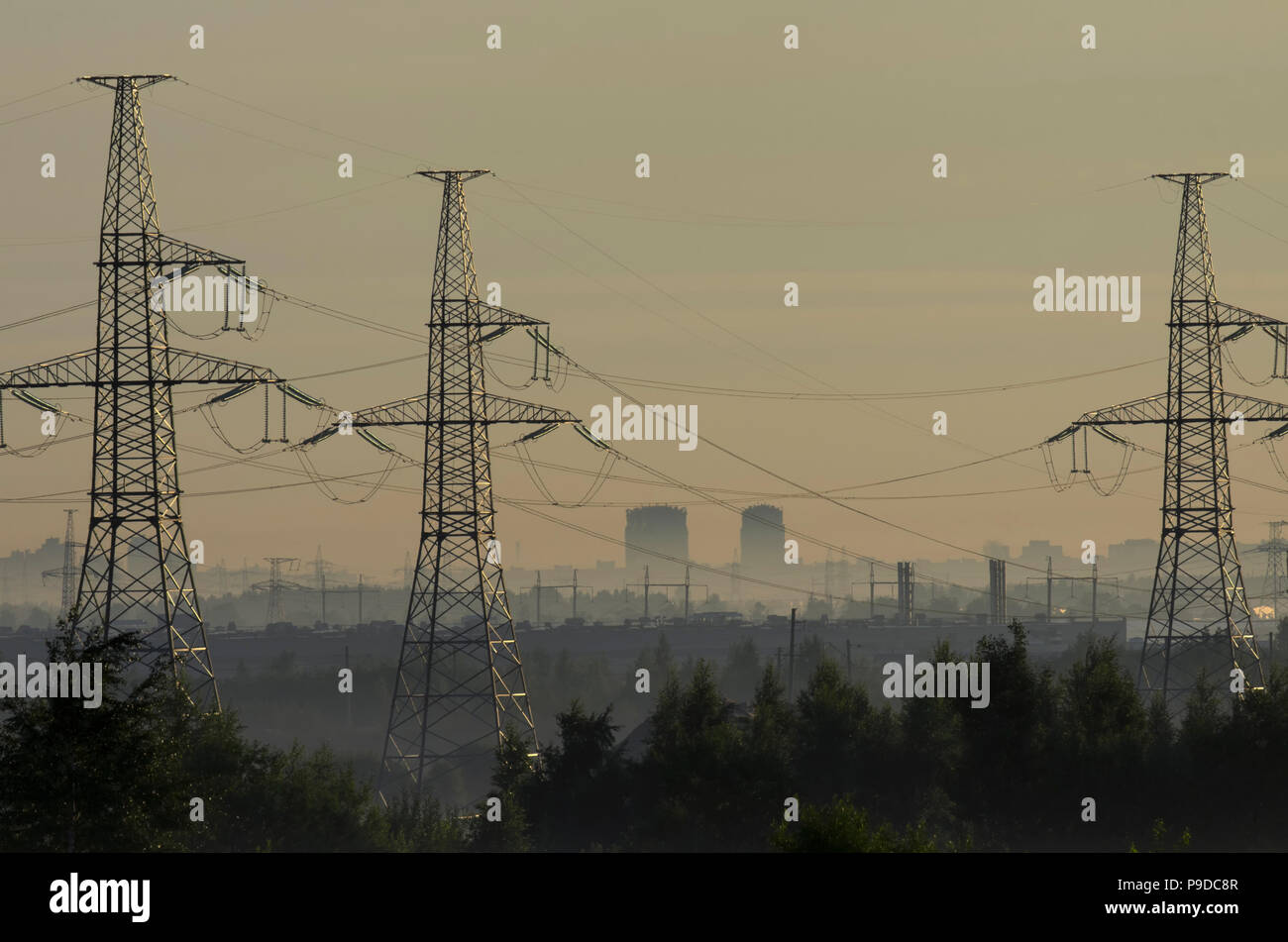 Towers of power lines in the pre-dawn fog on the outskirts of the city ...