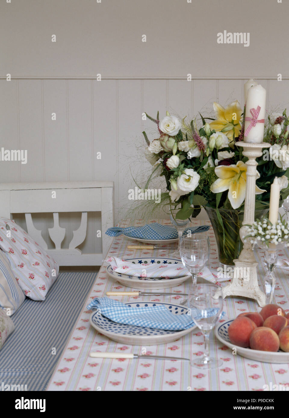 Summer flower arrangement on table set for lunch with a floral cloth ...