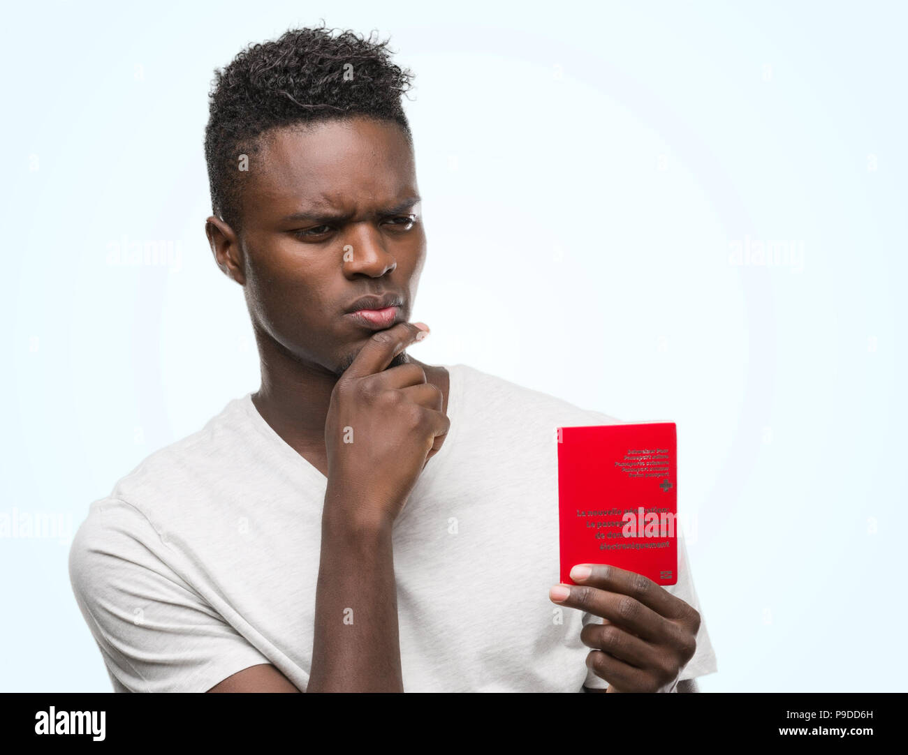 Young african american man holding passport of Switzerland serious face ...