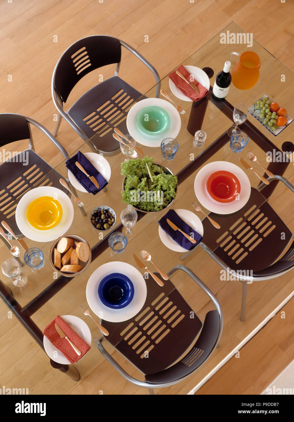 Aerial view of colourful bowls on white plates on glass table in modern ...