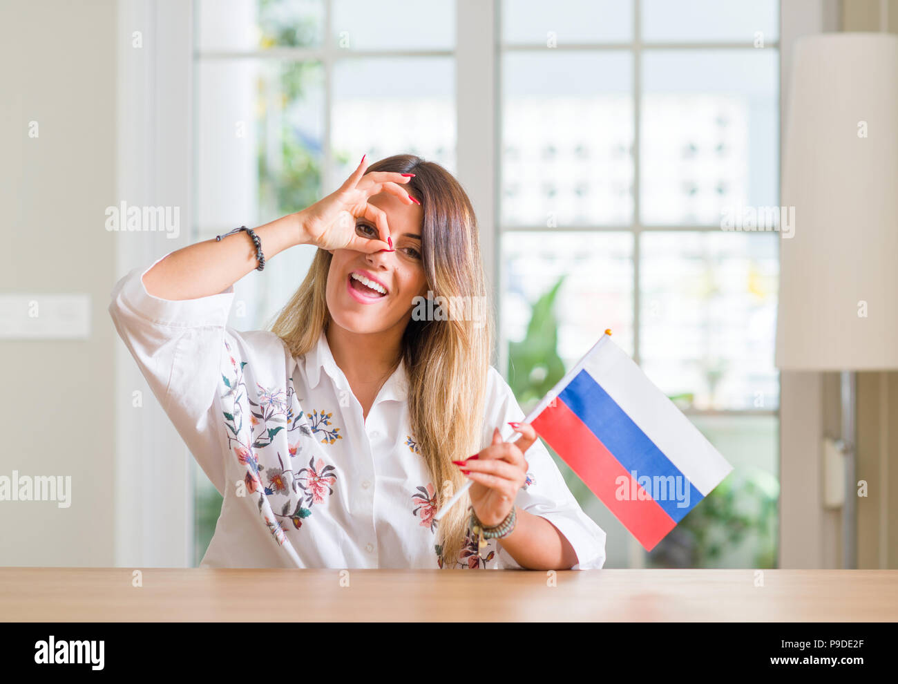Young woman at home holding flag of Russia with happy face smiling ...