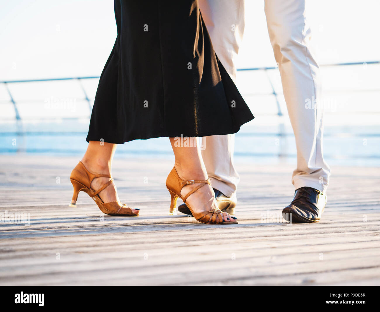 Young attractive couple dancing latin bachata near sea or ocean. Sunlight background. Summer ...