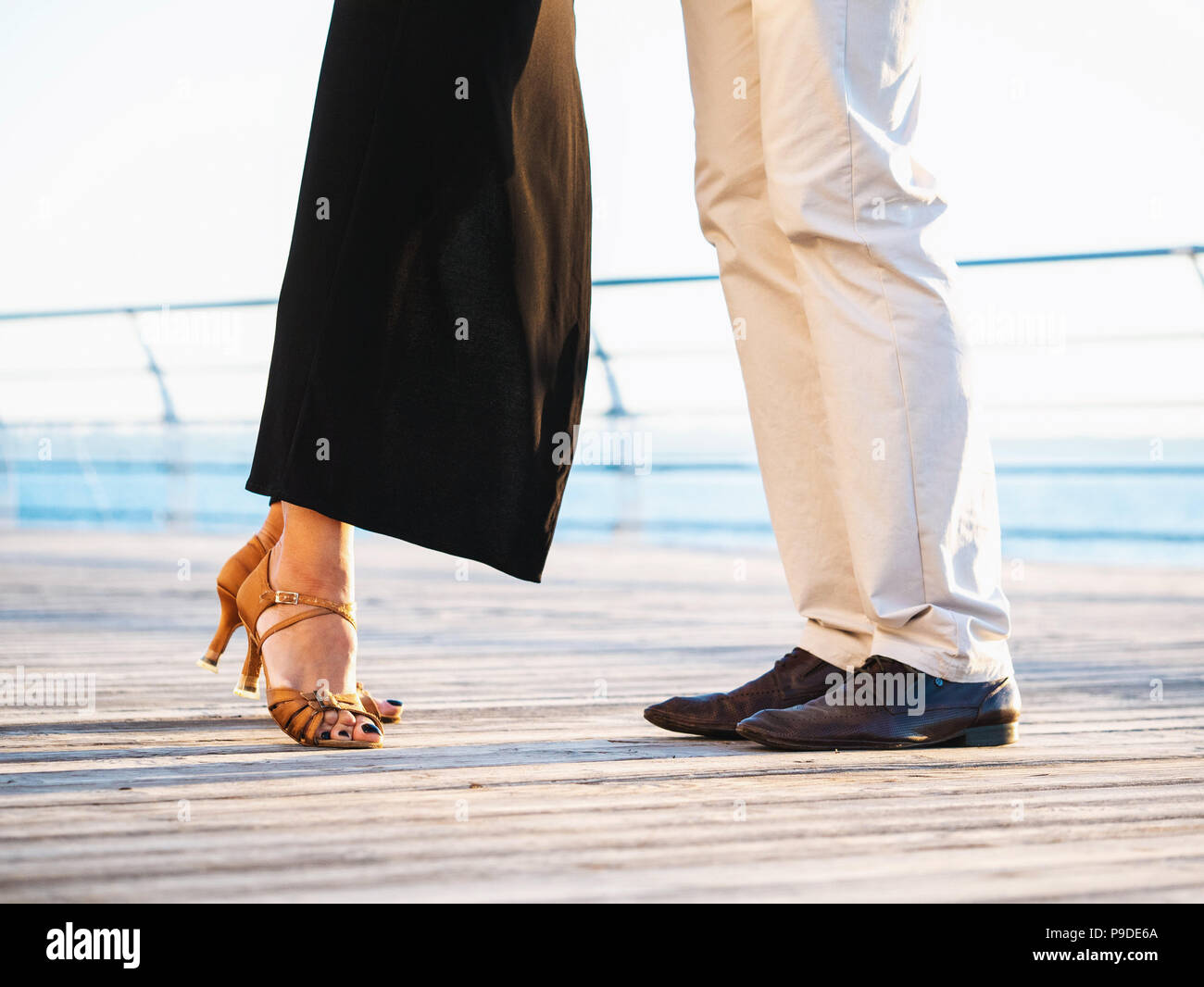 Young attractive couple dancing latin bachata near sea or ocean. Sunlight background. Summer ...