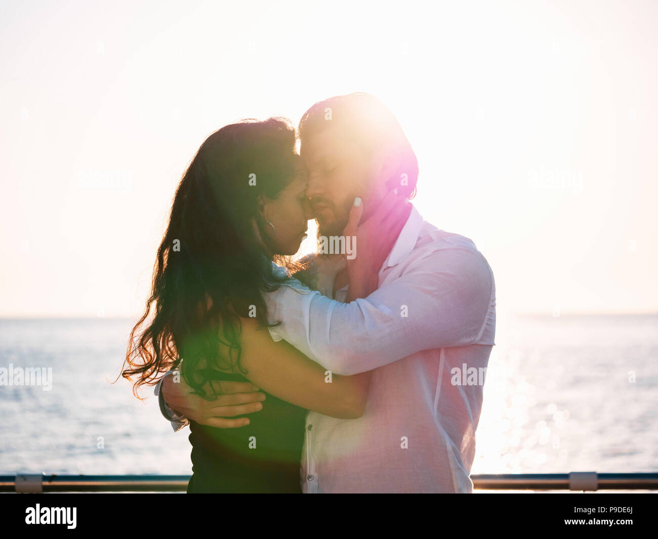 Portrait of young attractive couple dancing latin bachata near sea or ocean. Sunlight background ...