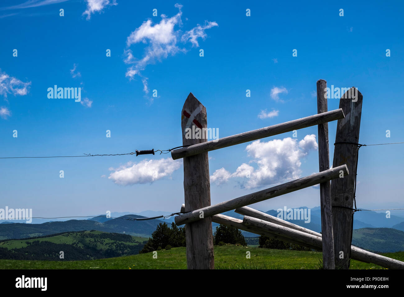 Narrow gateway through an electric fence post marked with a red and ...