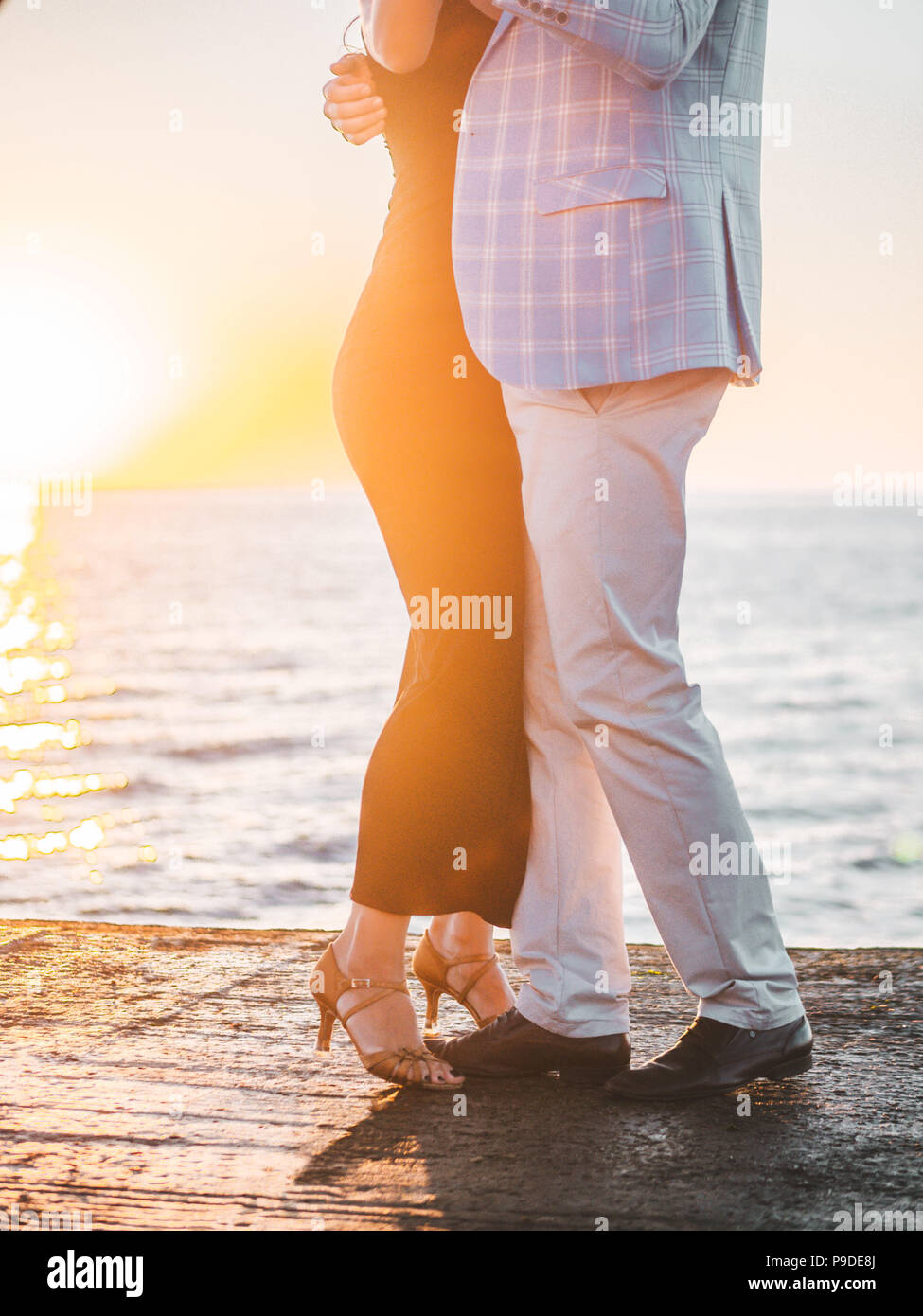 Young attractive couple dancing latin bachata near sea or ocean. Sunlight background. Summer ...