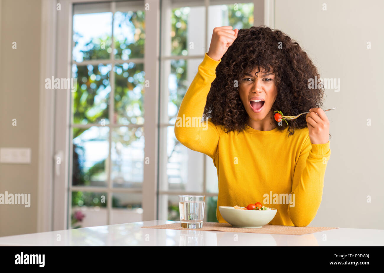 African american woman eating pasta salad annoyed and frustrated ...