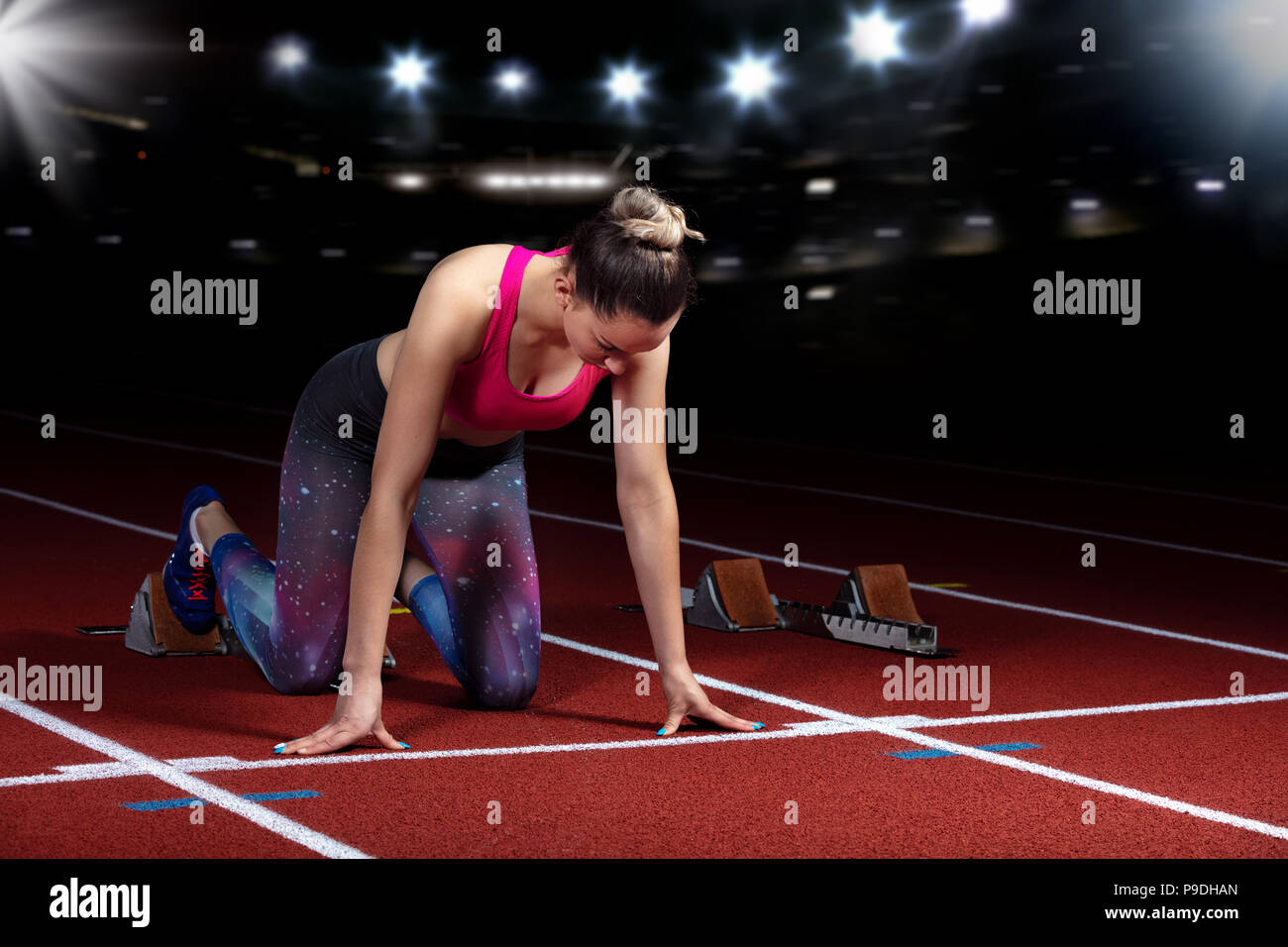 woman sprinter leaving starting blocks on the athletic track. exploding ...