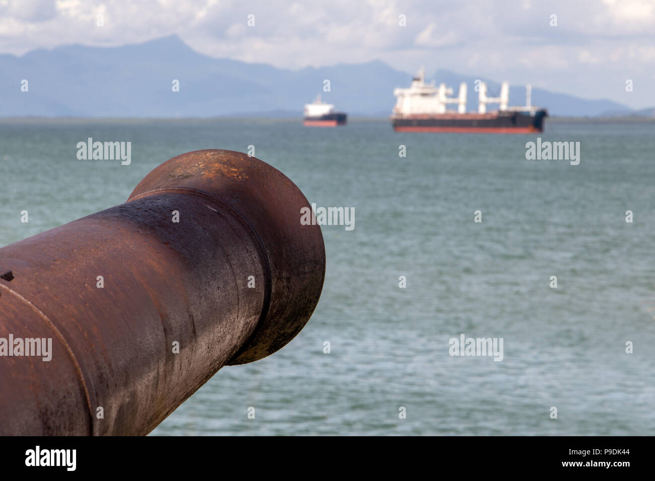 The old large caliber cannon aimed at the tanker ship on the sea ...