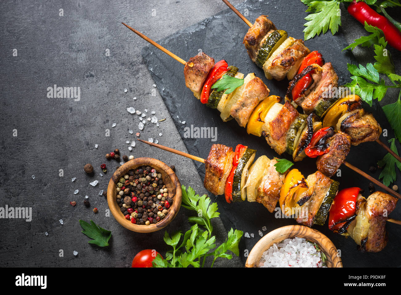 Grilled shish kebab or shashlik with vegetables on black stone table ...