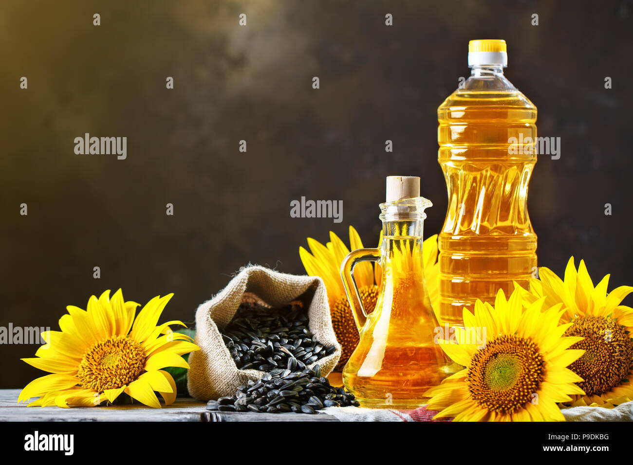 Closeup photo of sunflowers and sunflower oil with seeds on on a wooden ...
