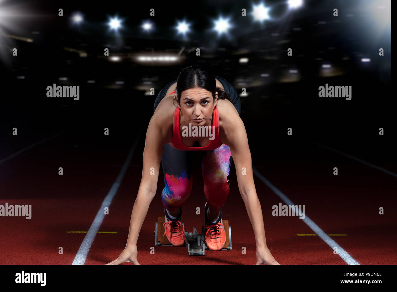 woman sprinter leaving starting blocks on the athletic track. exploding ...