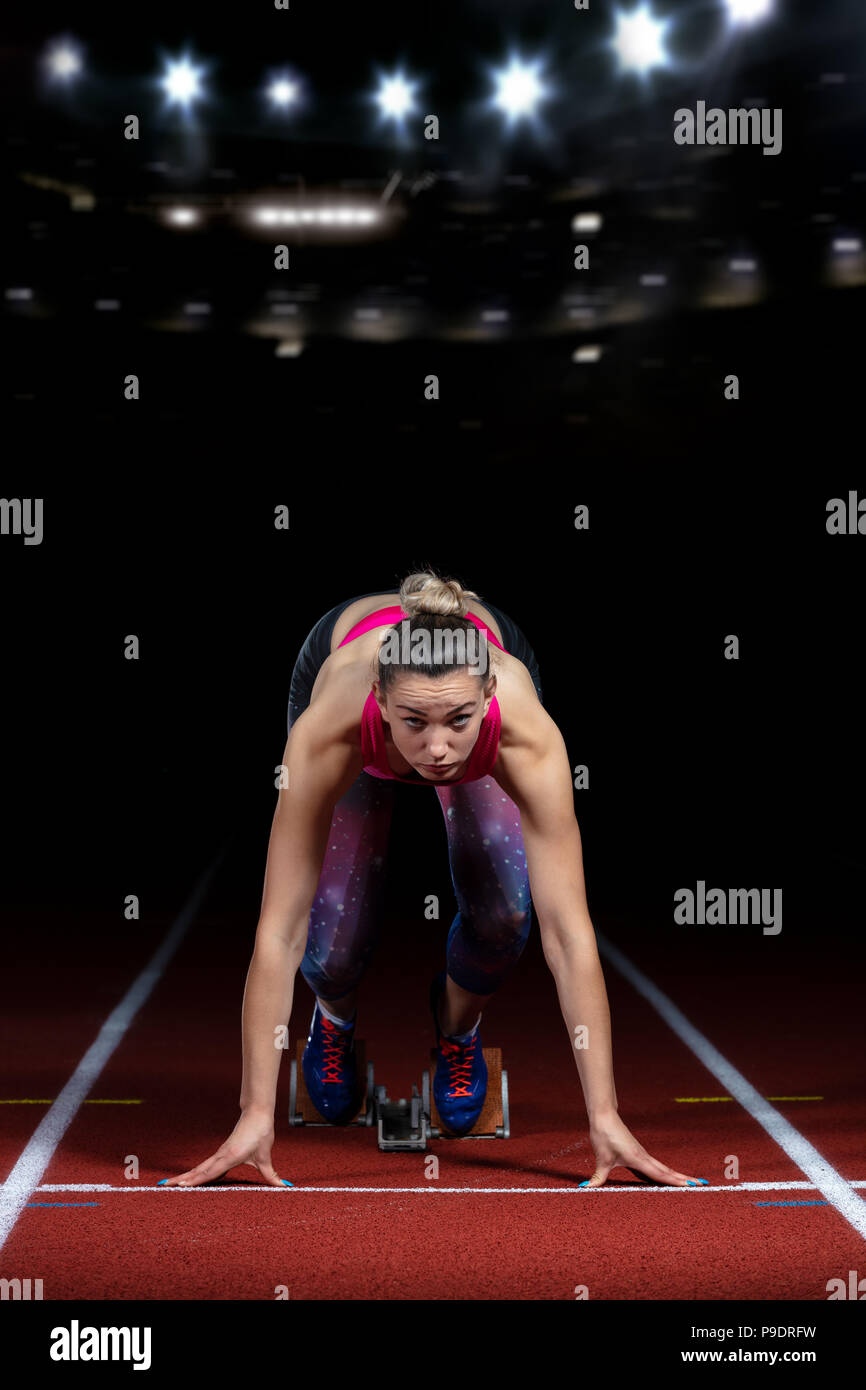 woman sprinter leaving starting blocks on the athletic track. exploding ...